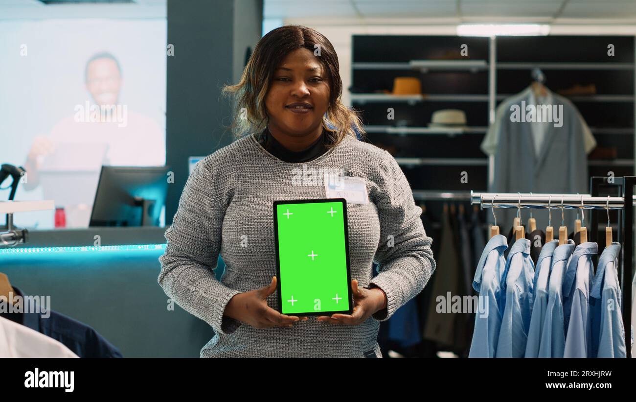 Young store manager showing tablet with green screen, advertising ...