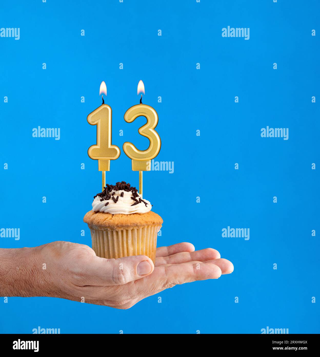 Hand delivering birthday cupcake - Candle number 13 on blue background ...
