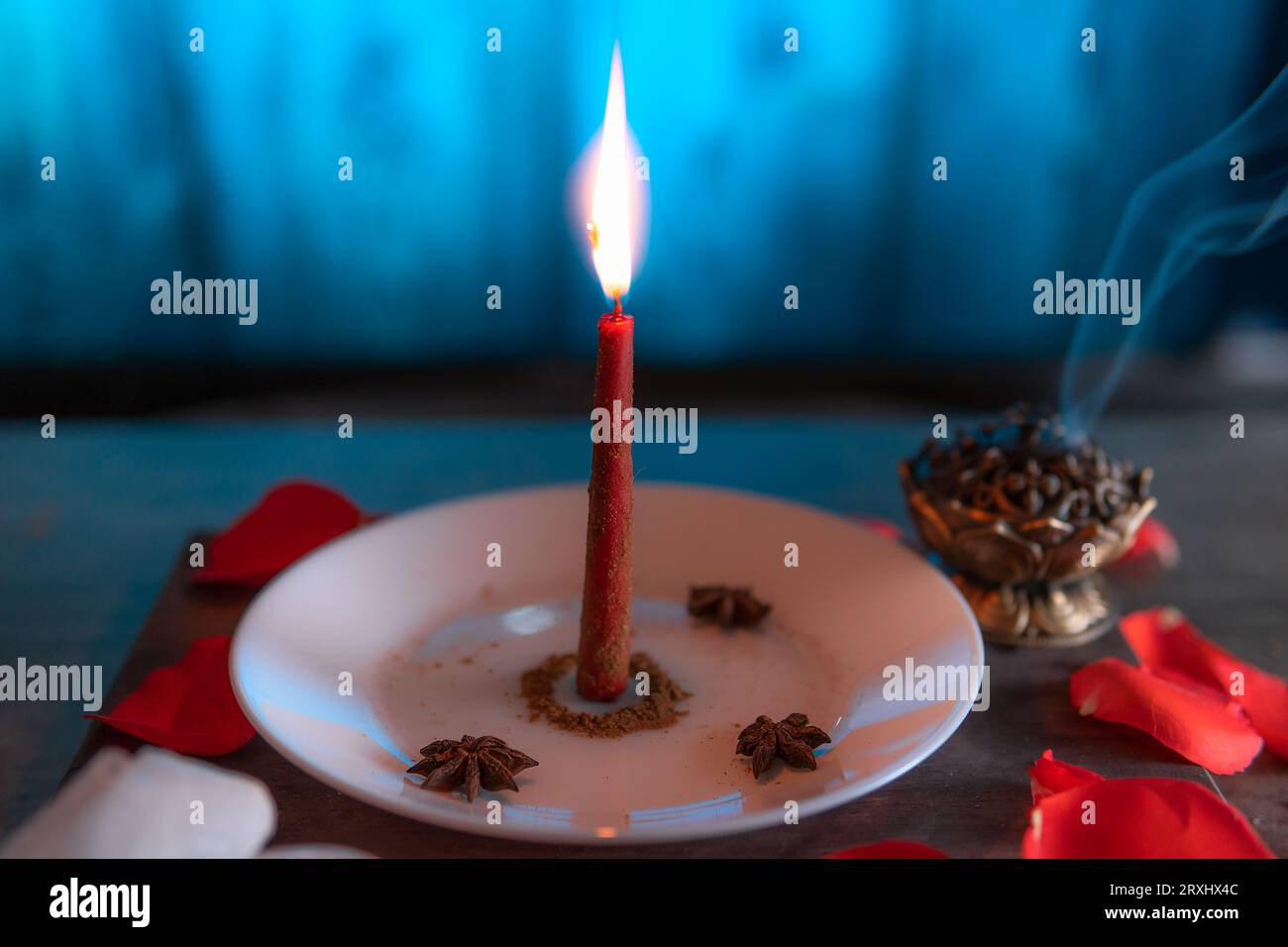 A red candle lit on a blue background, prepared with ground cinnamon ...