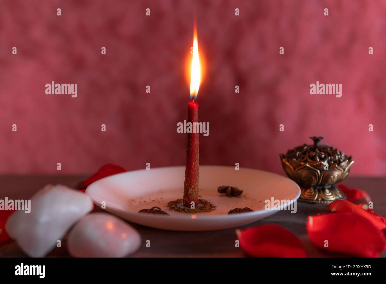 A red candle lit on a pink background, prepared with ground cinnamon ...