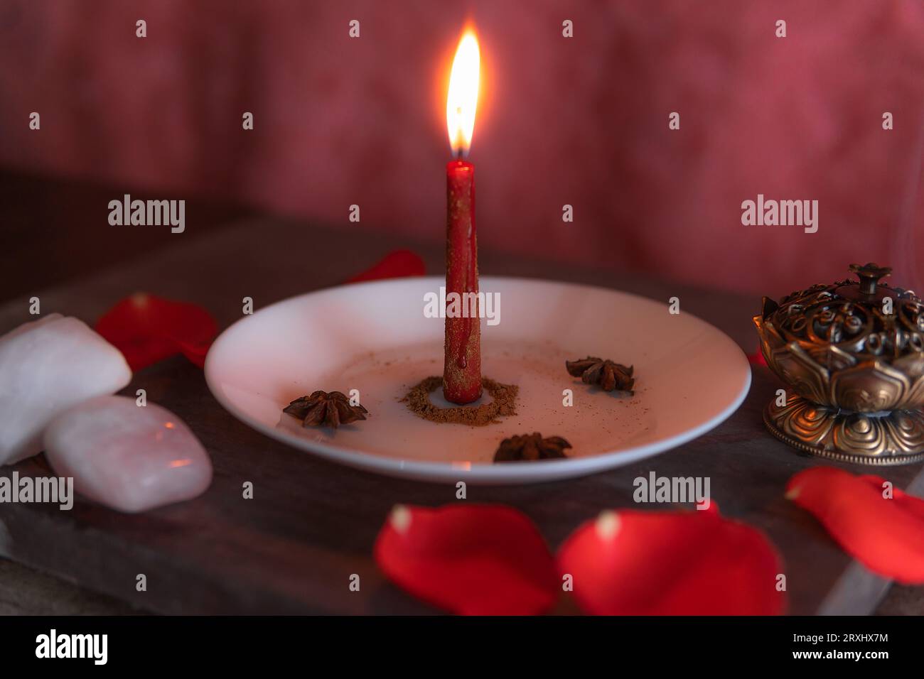 A red candle lit on a pink background, prepared with ground cinnamon ...
