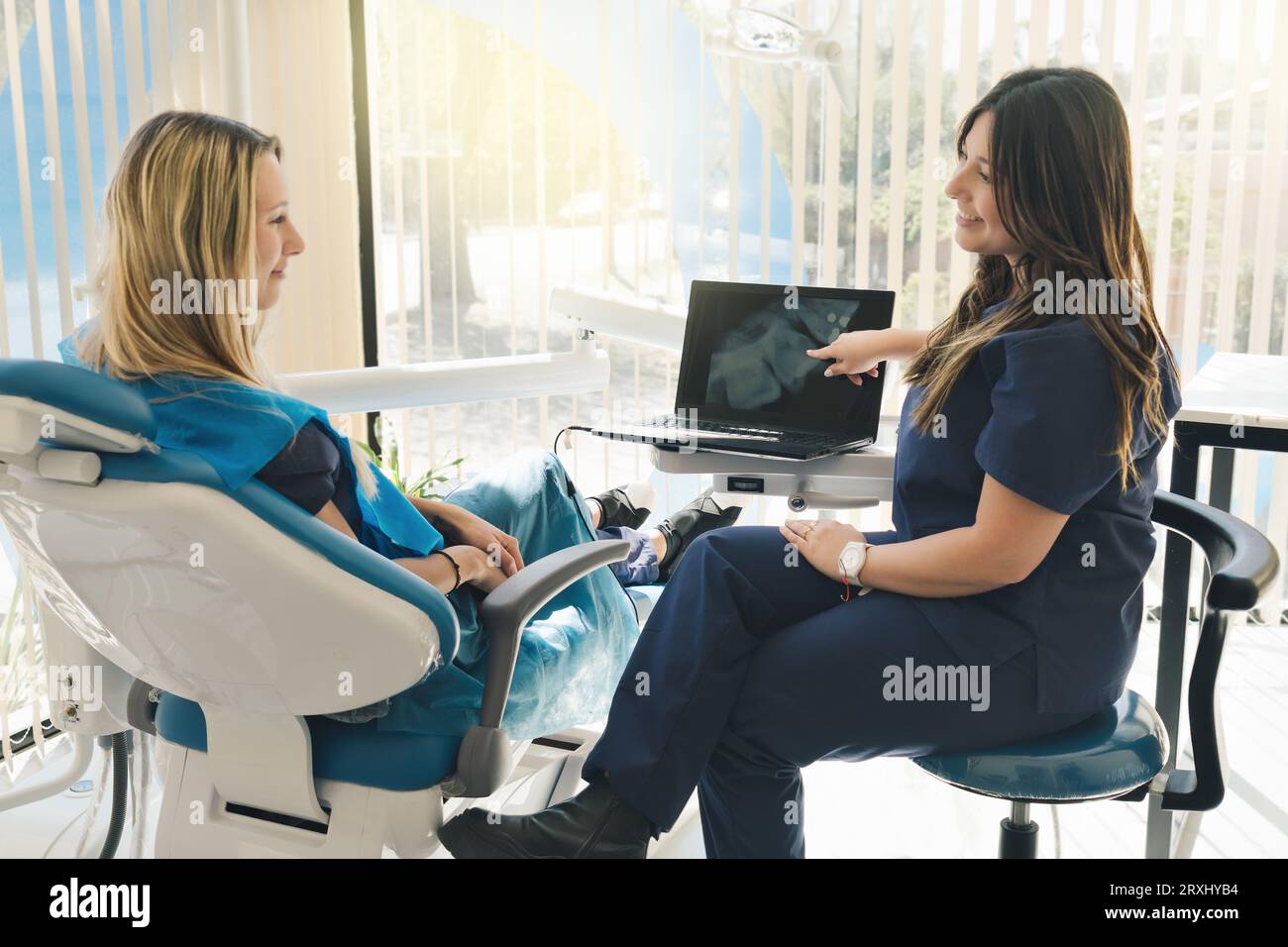 Doctor explains to her patient the digital X-ray images on a computer ...