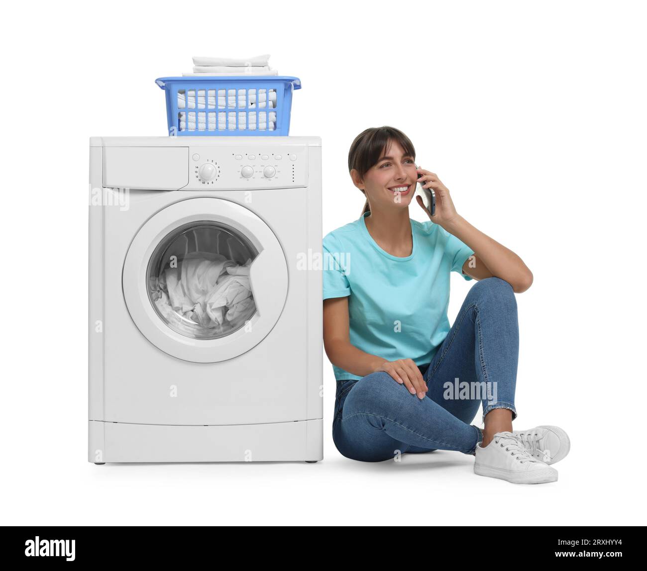 Beautiful woman talking on smartphone near washing machine with laundry ...