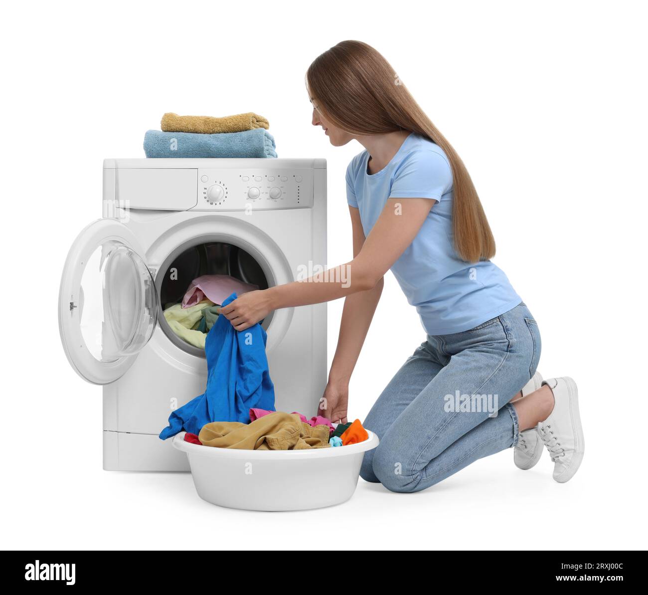 Beautiful young woman taking laundry out of washing machine on white ...