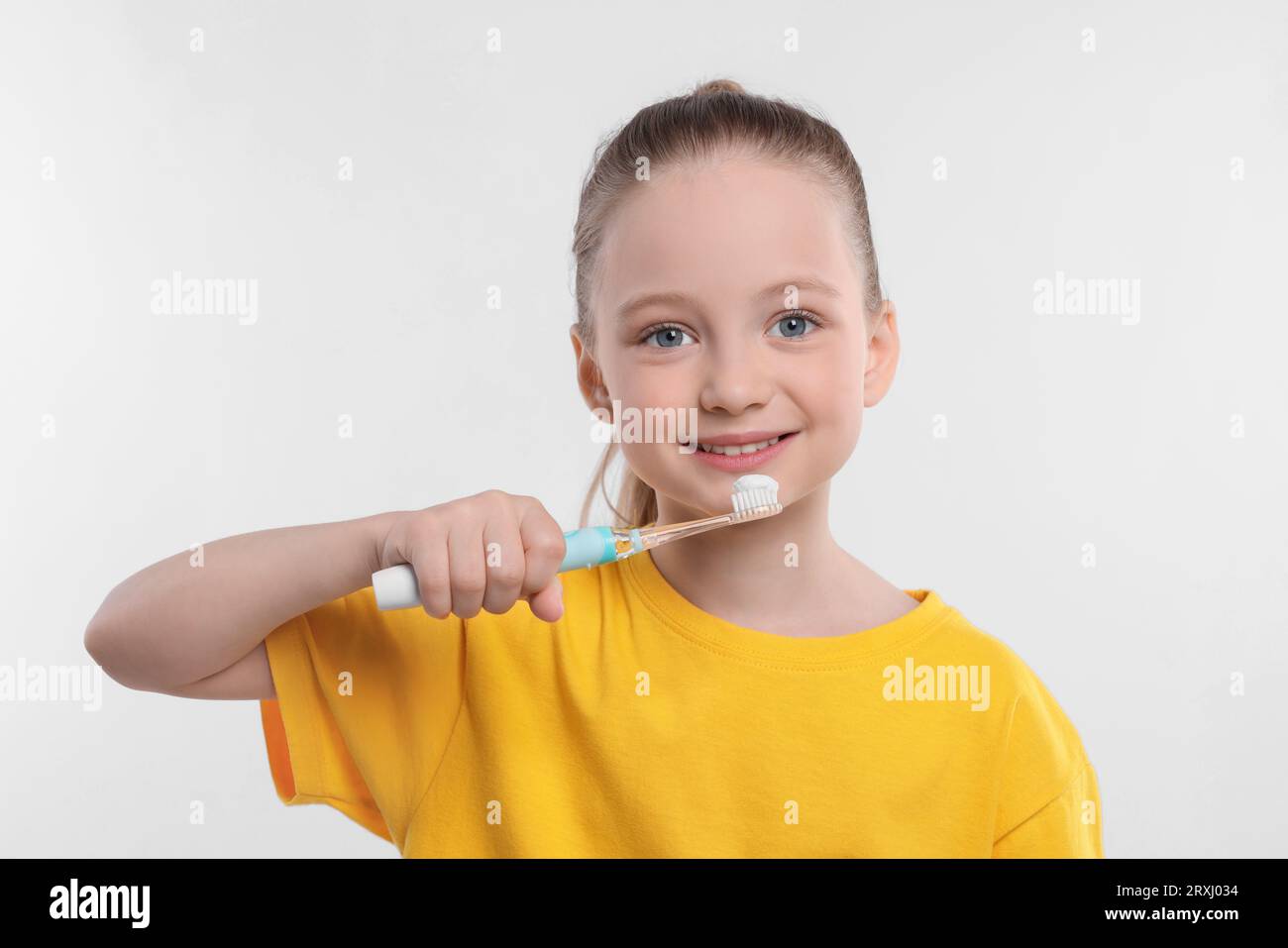 Happy girl brushing her teeth with electric toothbrush on white ...