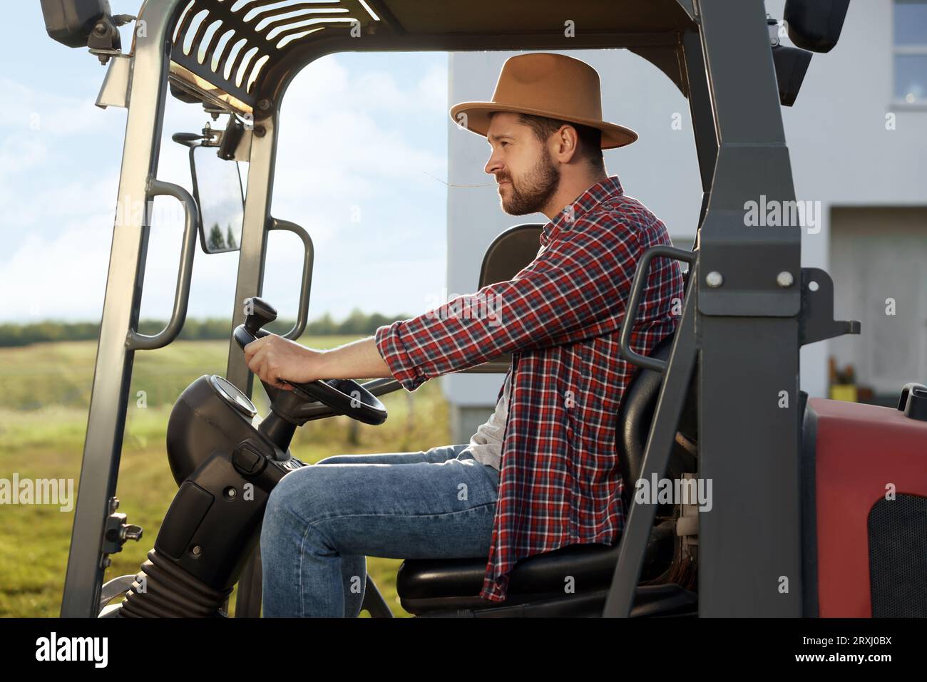 Farmer in hat driving loader outdoors. Agriculture equipment Stock ...