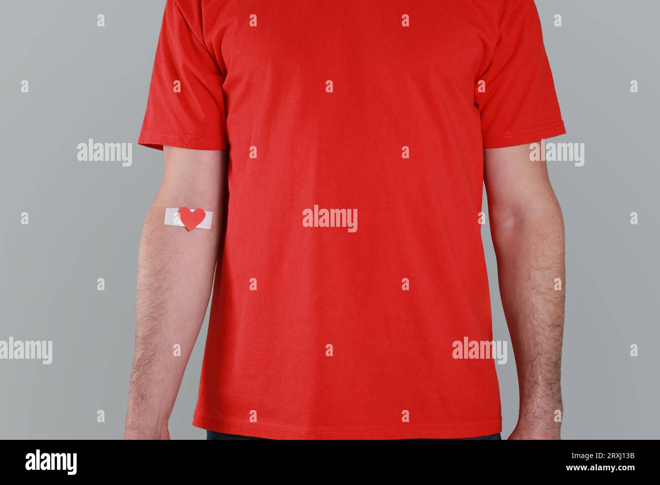 Blood donation concept. Man with adhesive plaster on arm against grey ...