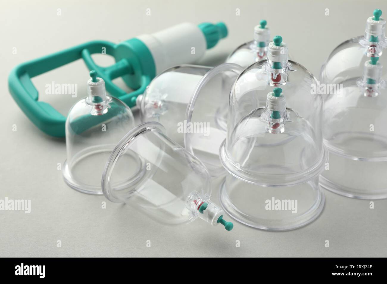 Plastic cups and hand pump on light grey background, closeup. Cupping ...