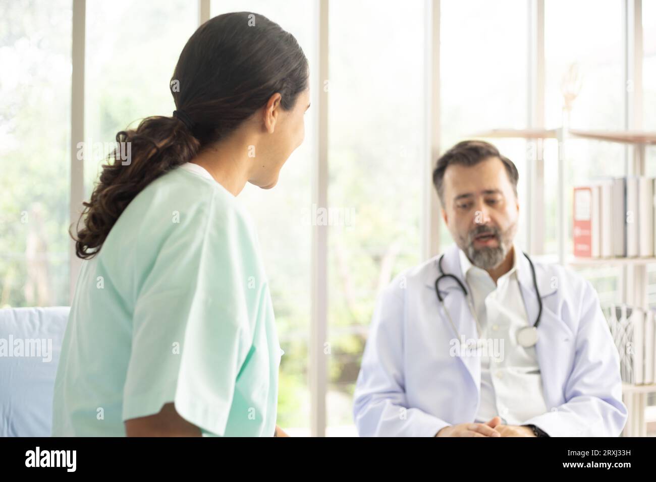 Relaxing Caucasian male physician with Hispanic female patient. The ...