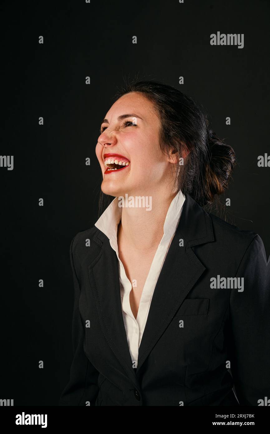 Laughing woman in black business outfit against a black background ...