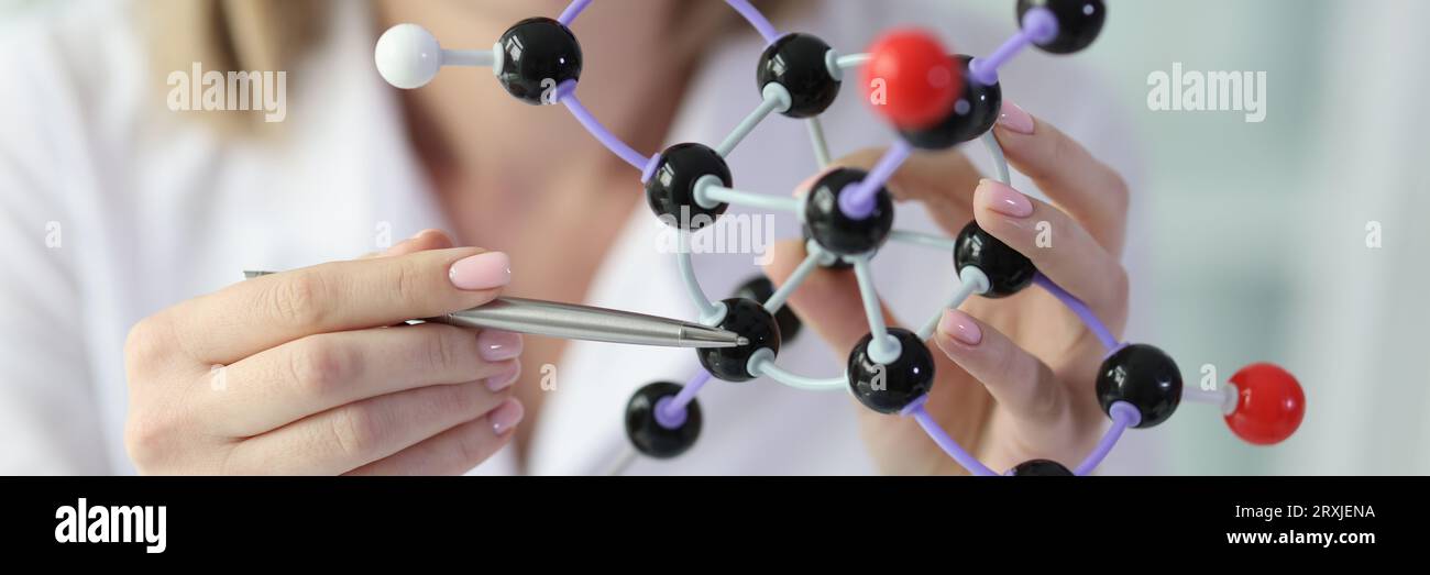 Female scientist holds model of molecular structure and points to one ...