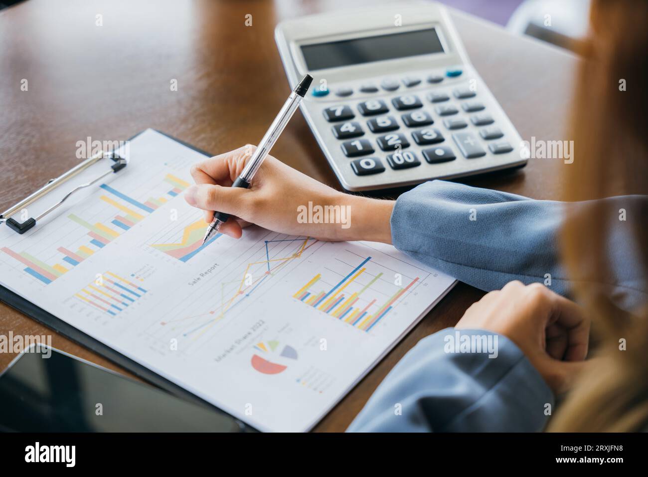 businesswoman working with paperwork charts and graphs and calculator ...