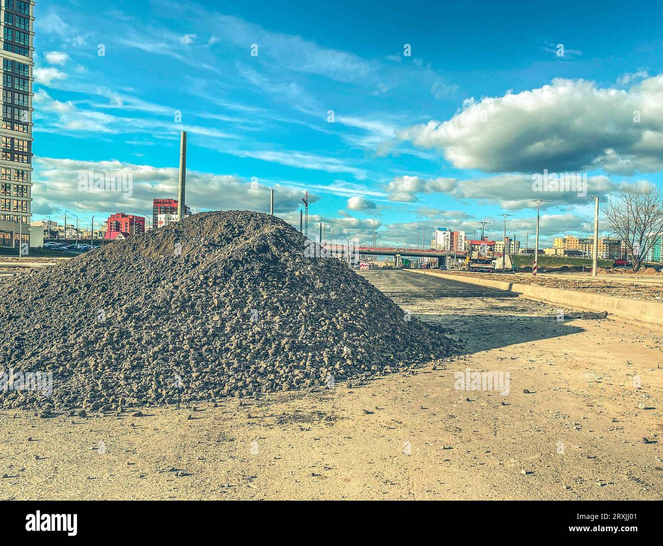 construction site. a mound of stones and sand next to tall houses under ...