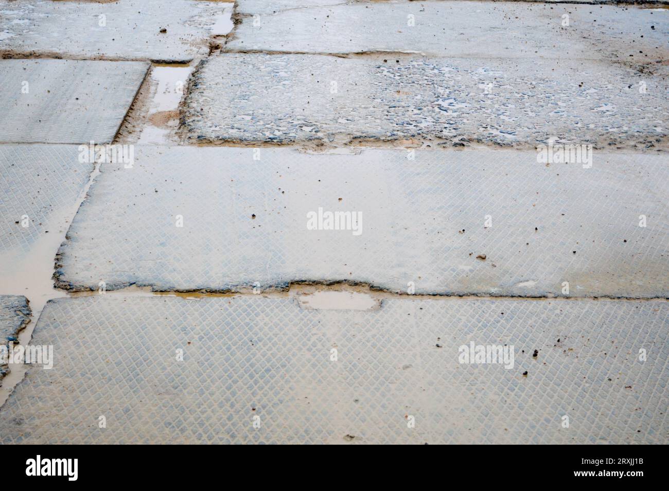 Bad concrete dirty road of blocks and slabs with seams and cracks ...