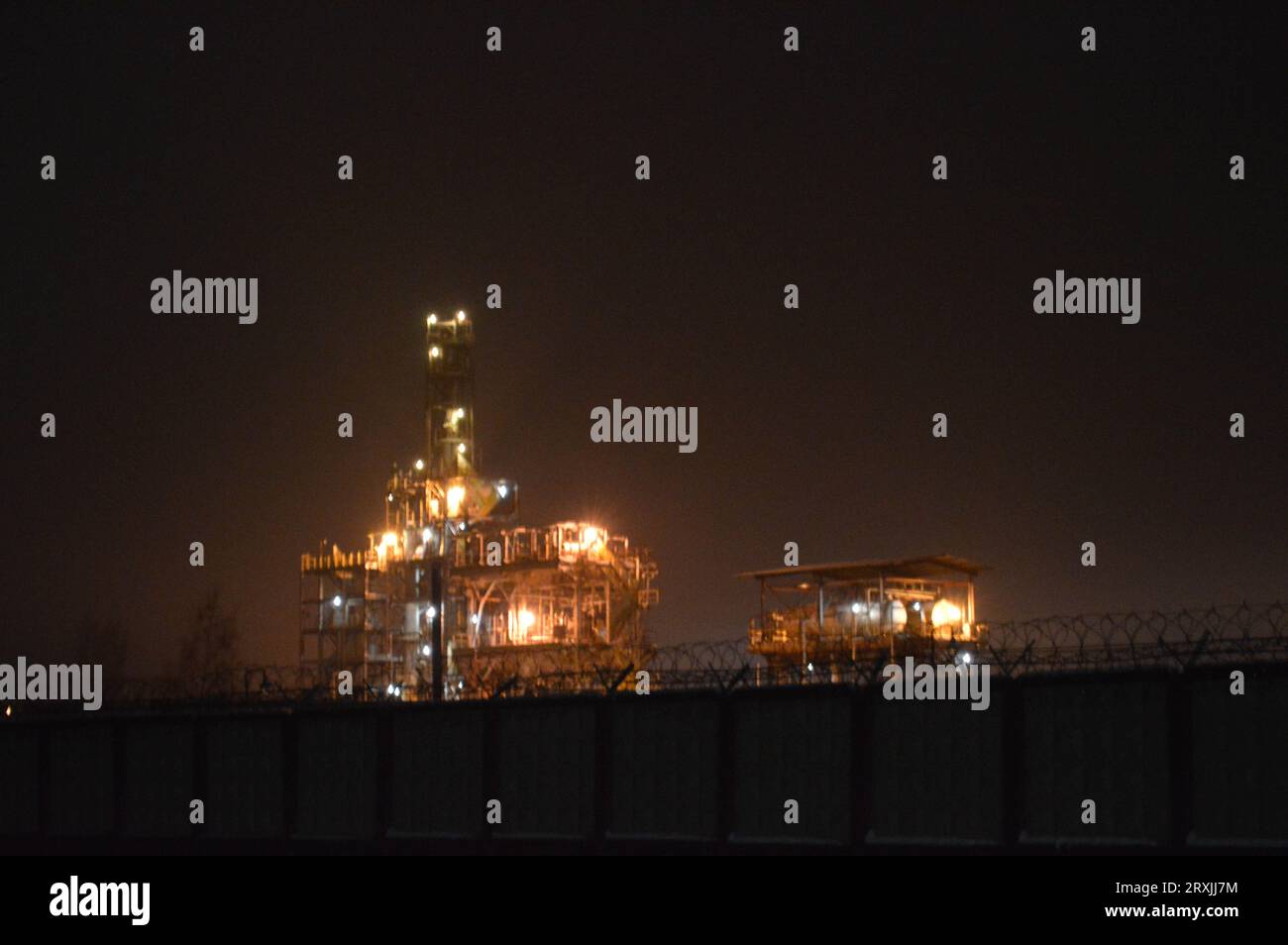 Night photo of an oil refinery, a petrochemical plant through a fence ...