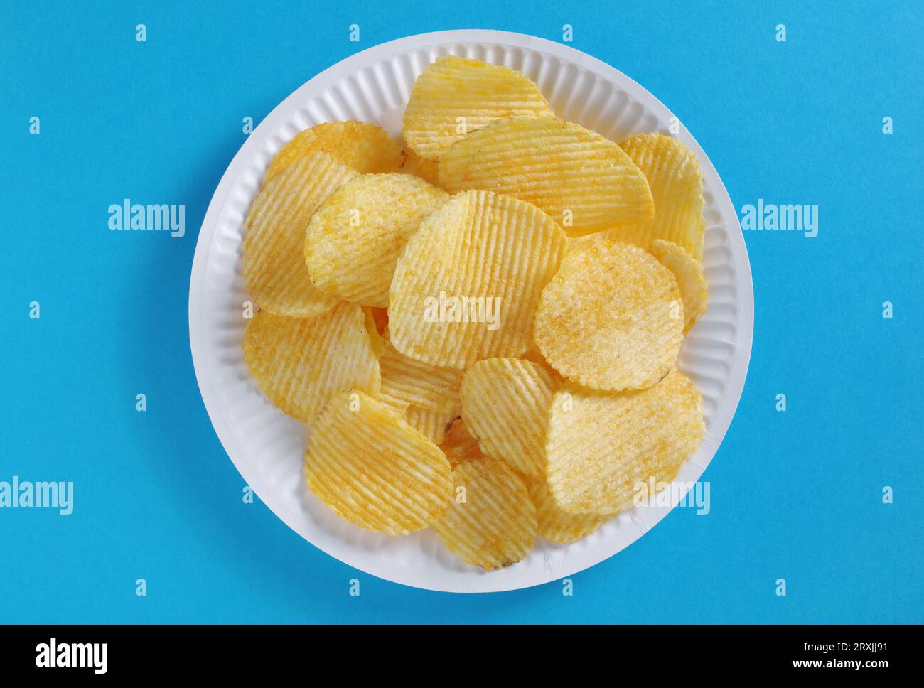 Ribbed potato chips in a paper plate on blue background, top view Stock ...