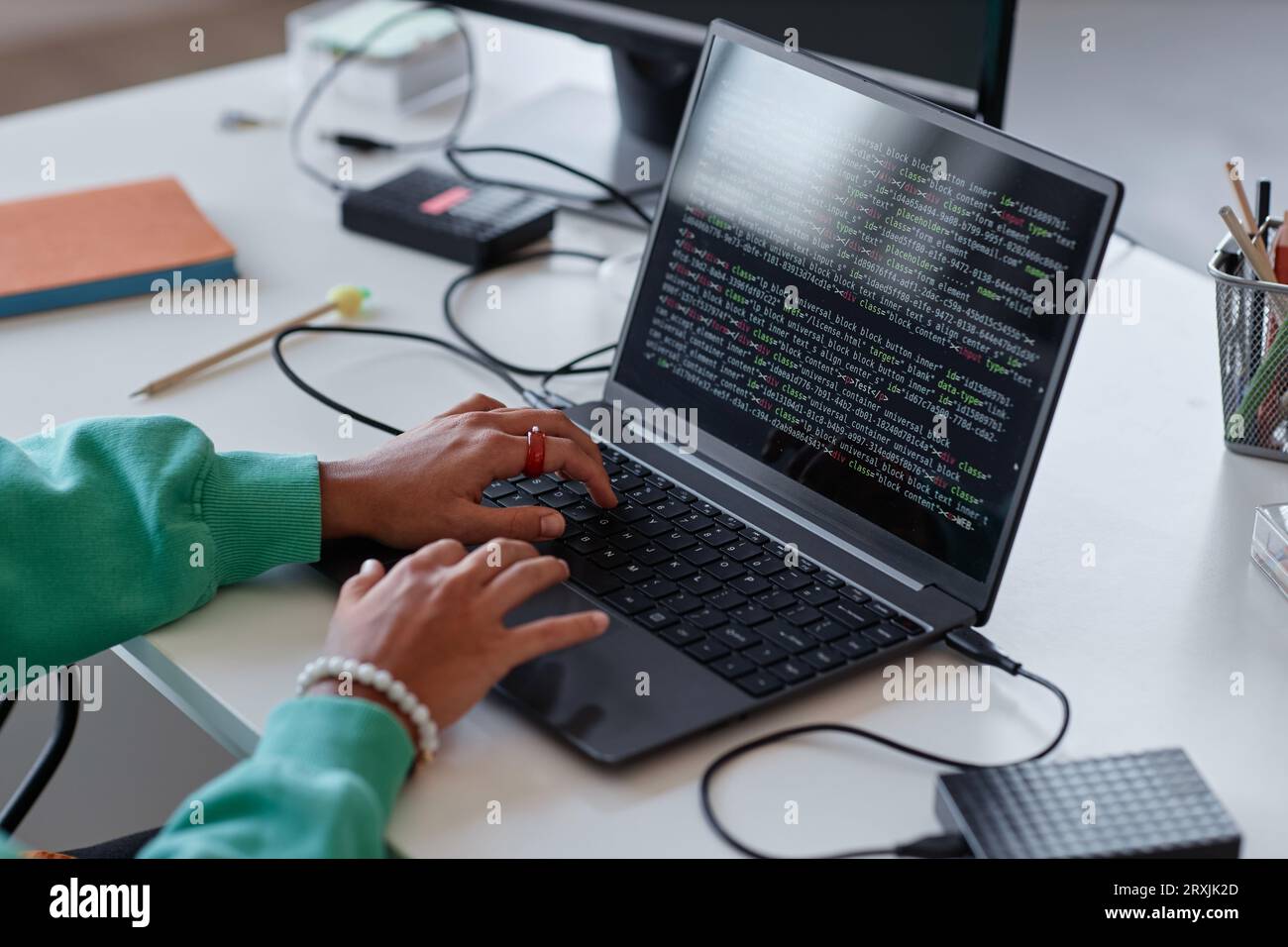 Close-up of woman typing codes on laptop while working at her workplace ...