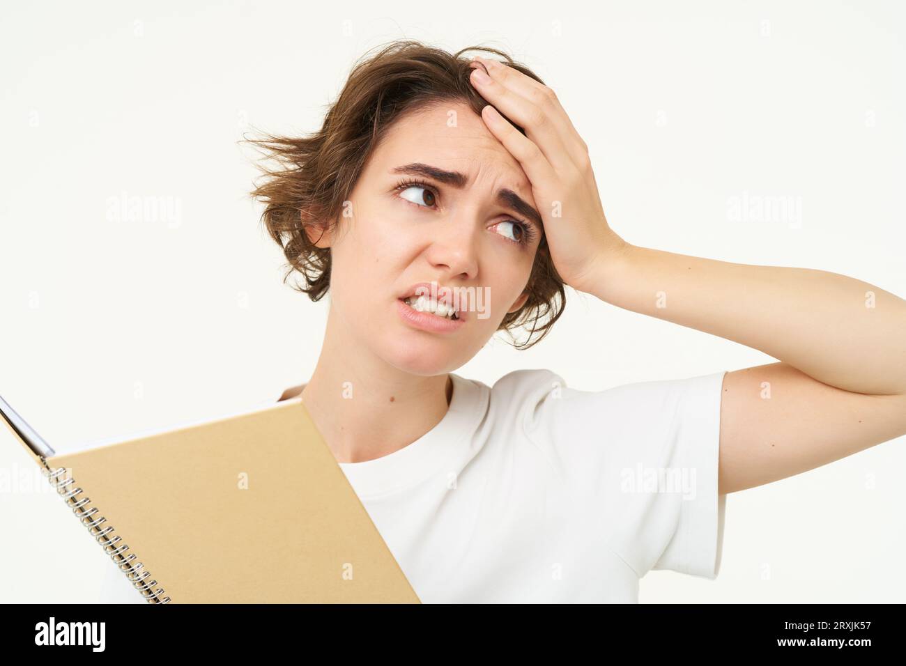 Portrait of puzzled, upset young woman tired of doing homework, holding ...