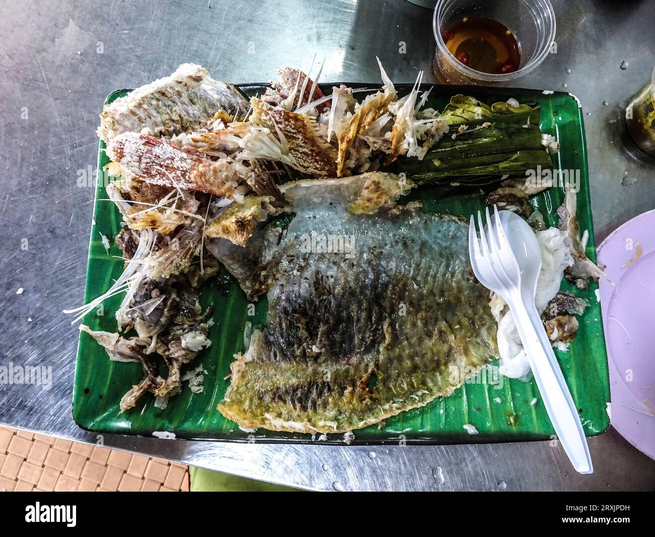 Dirty dish with leftover food, fish bones, and cutlery. End of lunch in ...