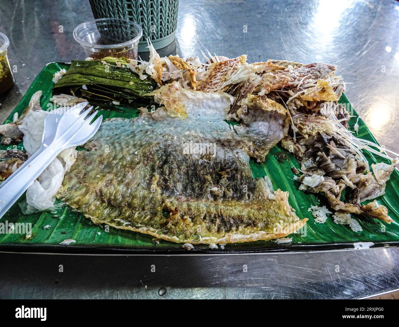 Dirty dish with leftover food, fish bones, and cutlery. End of lunch in ...