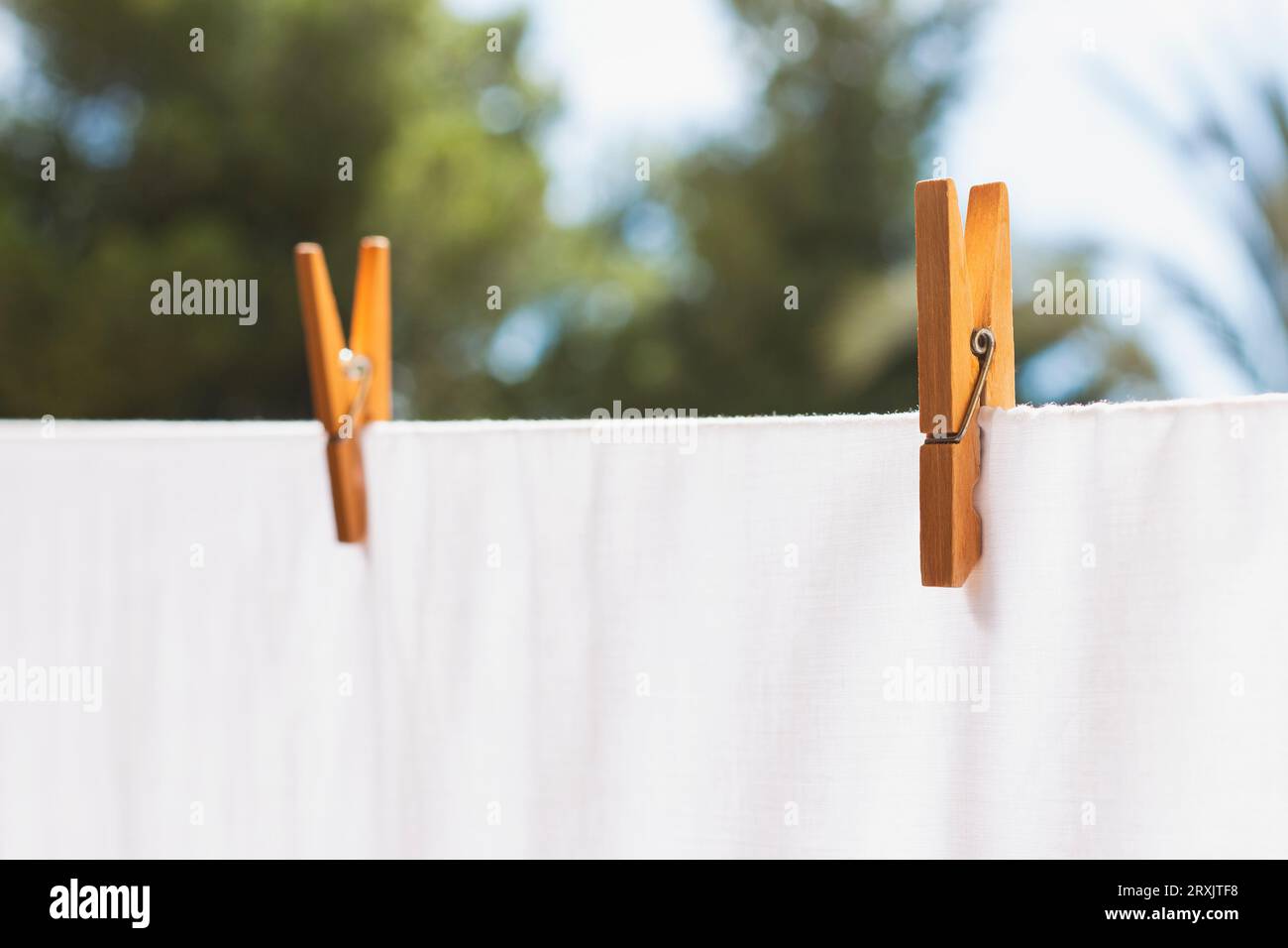 White cloth placed on clothesline while drying in sunlight and fastened ...