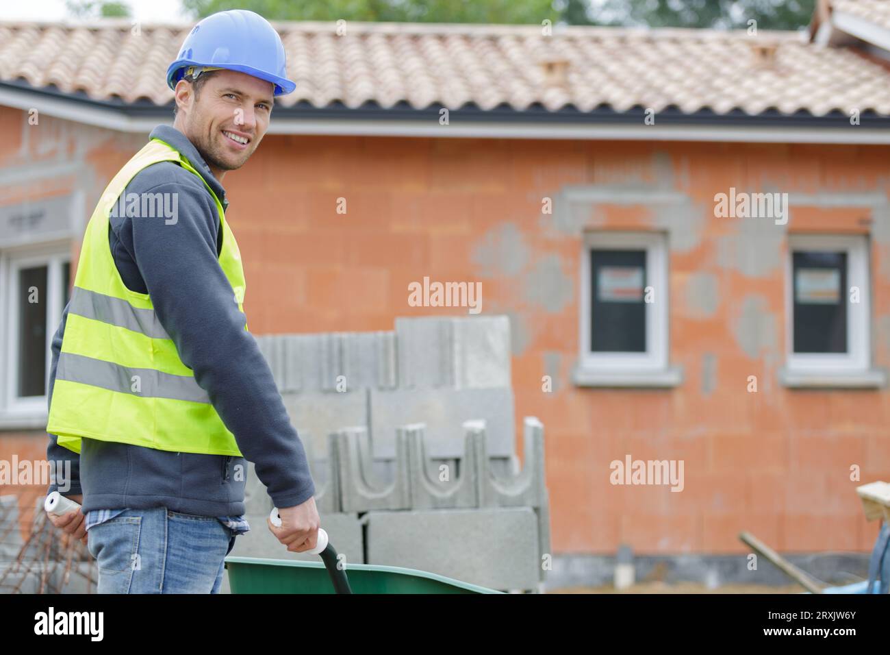 builder carrying blocks on a wheelbarrow at the construction site Stock ...