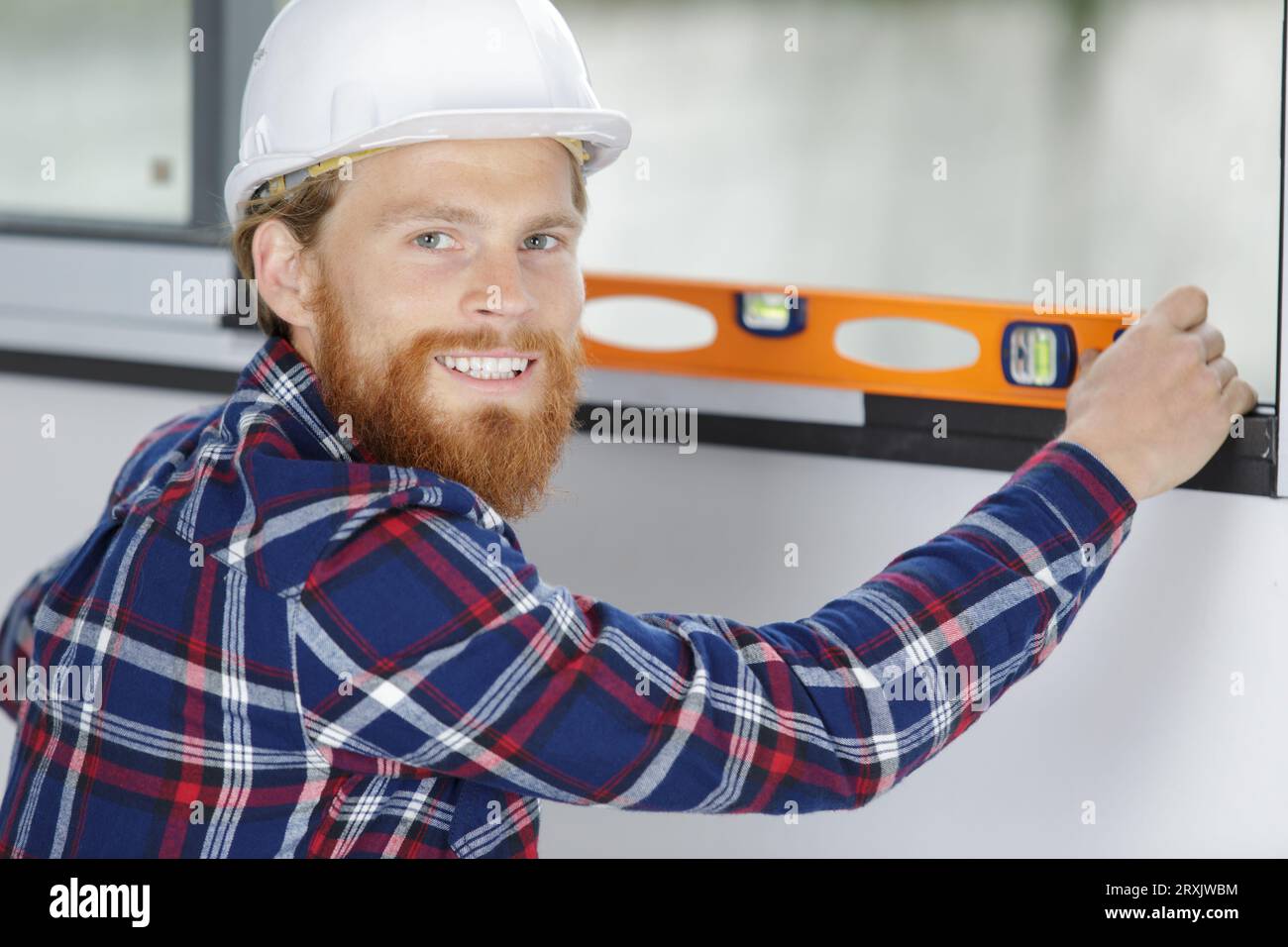 construction worker using bubble level while installing window indoors ...
