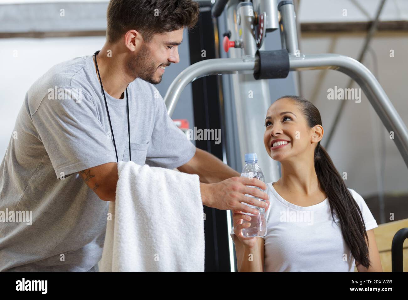 personal trainer passing water to young woman Stock Photo - Alamy