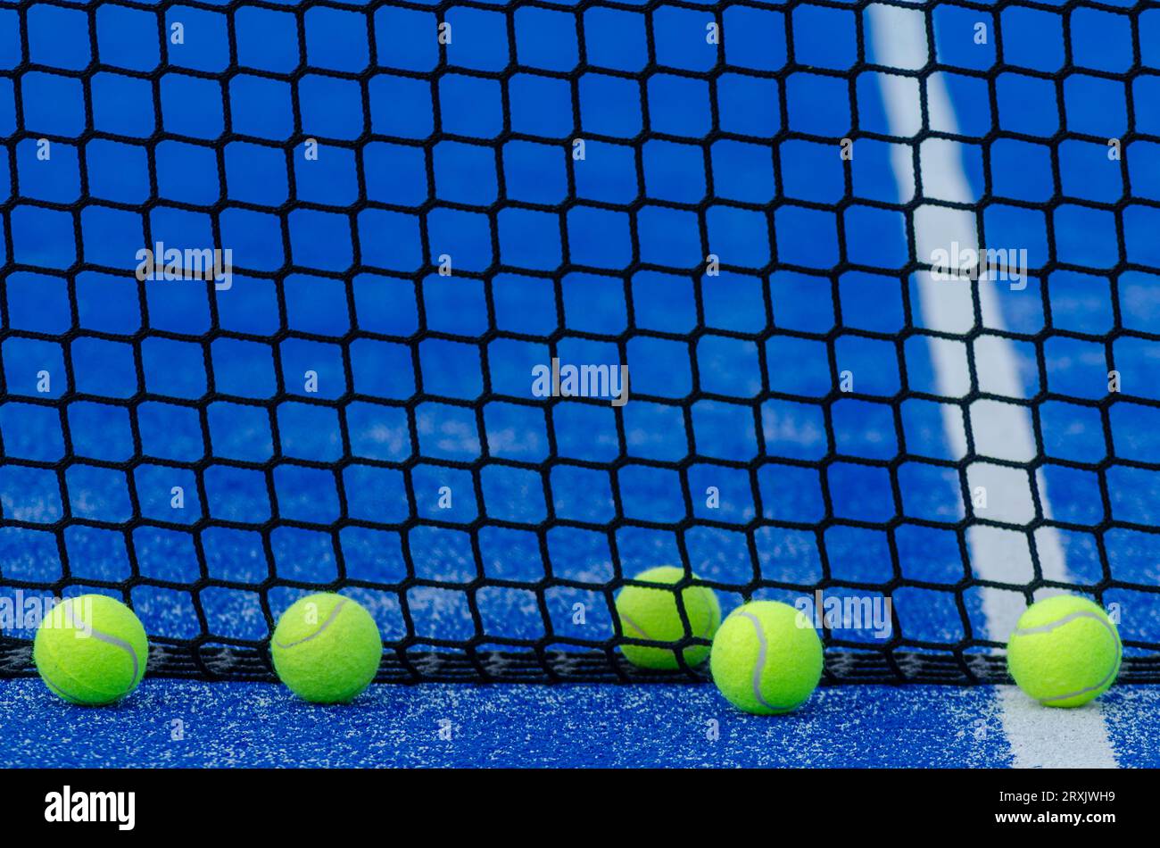 three paddle tennis balls close to the net of a paddle tennis court ...