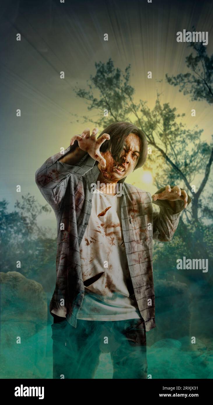 A scary zombie with blood and wounds on his body walking on a graveyard ...