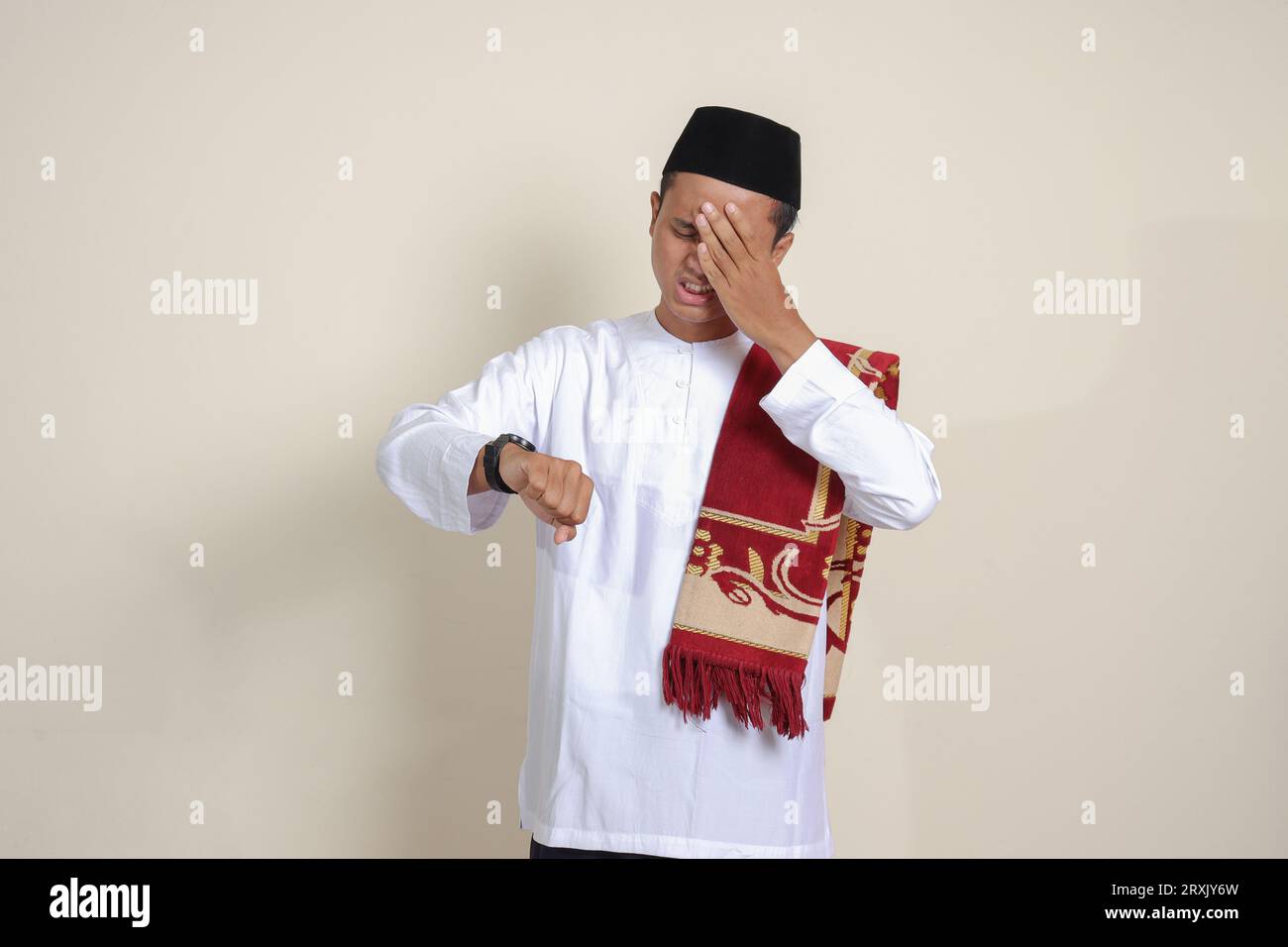 Portrait of attractive Asian muslim man in white shirt looking on wrist ...