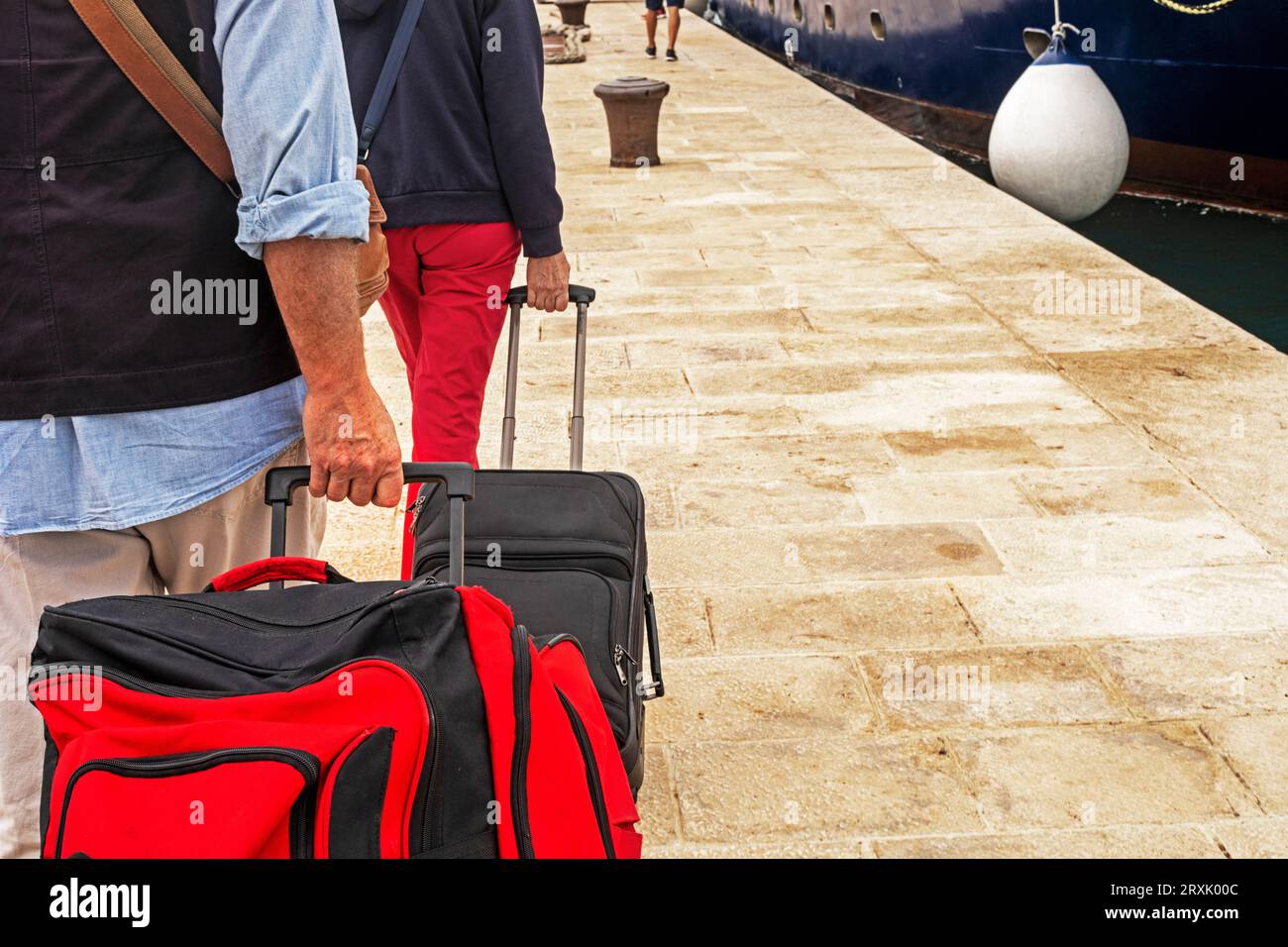 close-up of passengers on the liner carrying their luggage on wheels on ...