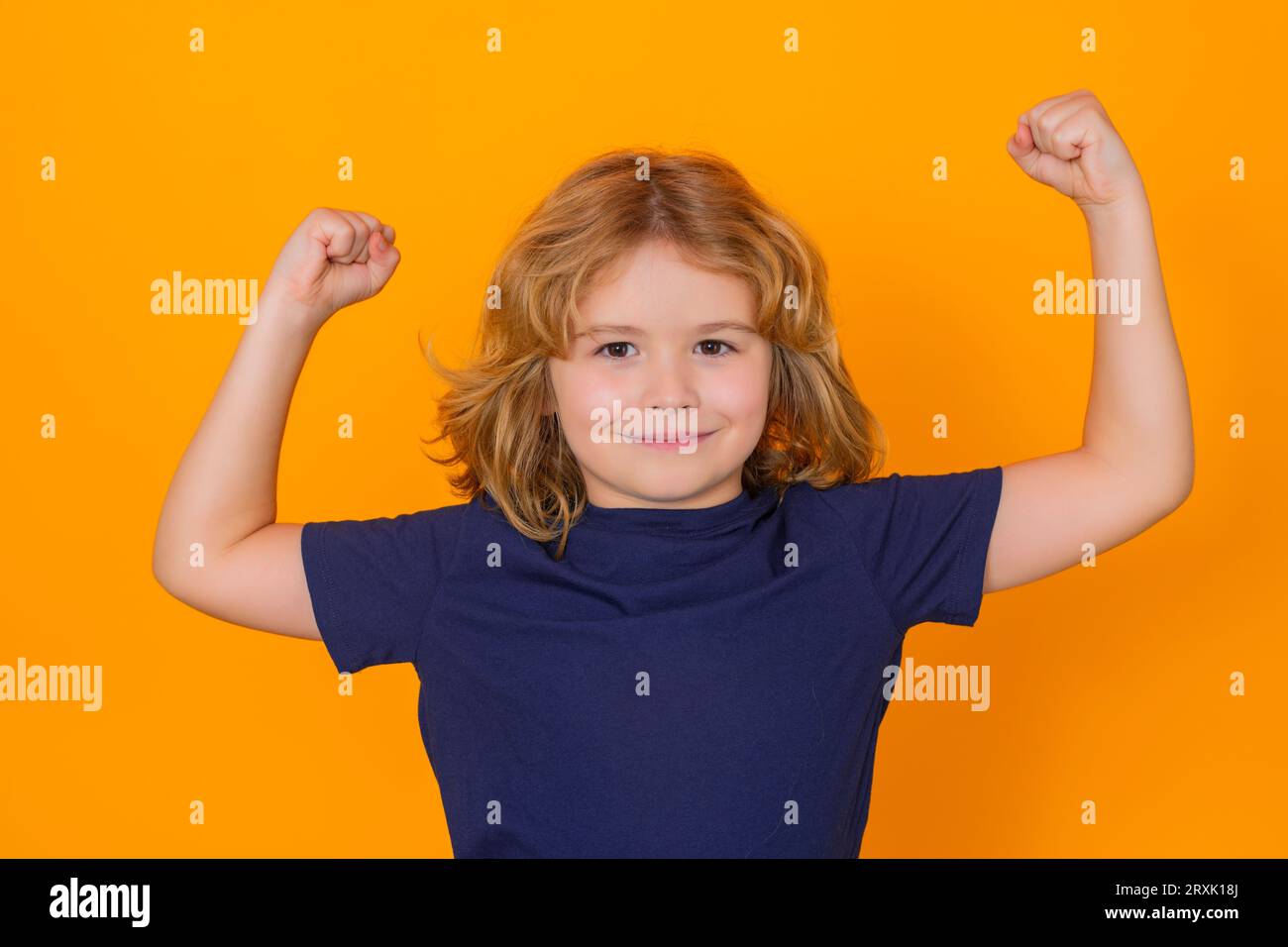 Cute child showing muscles on yellow studio isolated background. Power ...