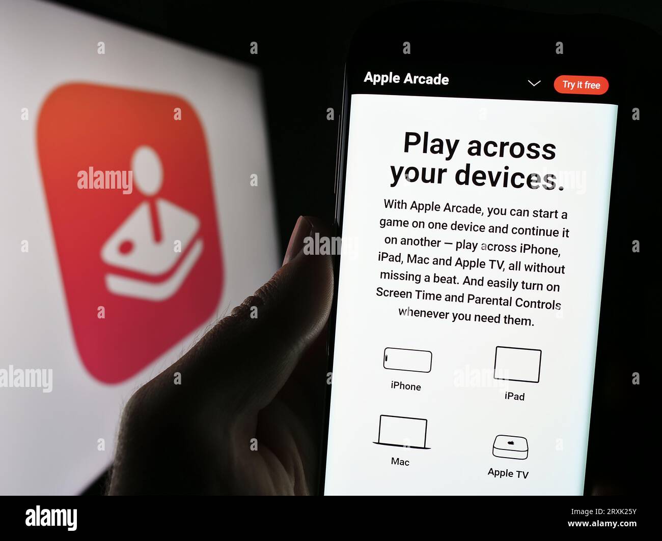 Person holding smartphone with webpage of video game platform Apple Arcade on screen in front of ...
