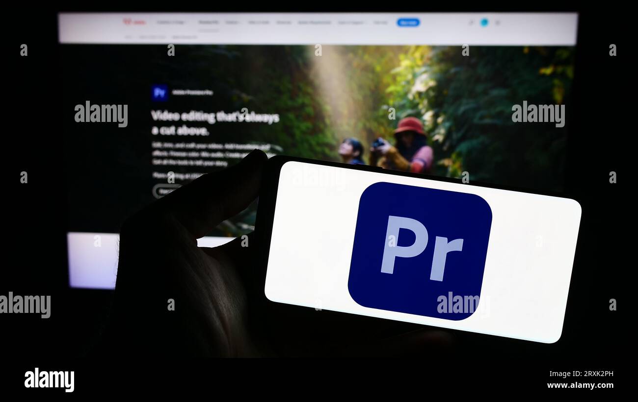 Person holding smartphone with logo of video editing software Adobe ...