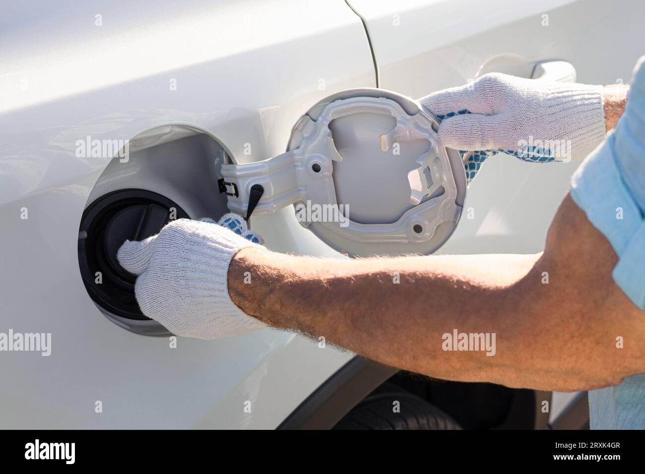 a man in gloves opens the cap of a gas tank of a car. hand holding gas ...