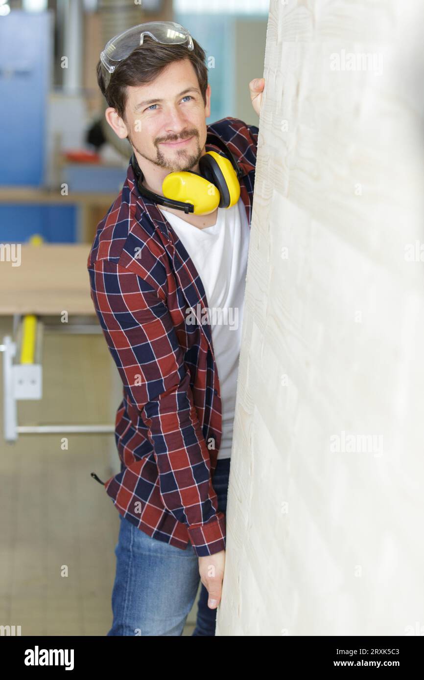 young man carrying large sheet of wood Stock Photo - Alamy