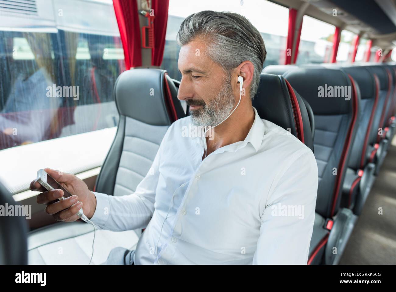male bus passenger charging his cellphone Stock Photo - Alamy