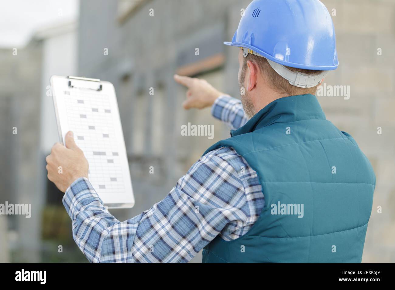 male builder in hard hat with clipboard pointing finger Stock Photo - Alamy