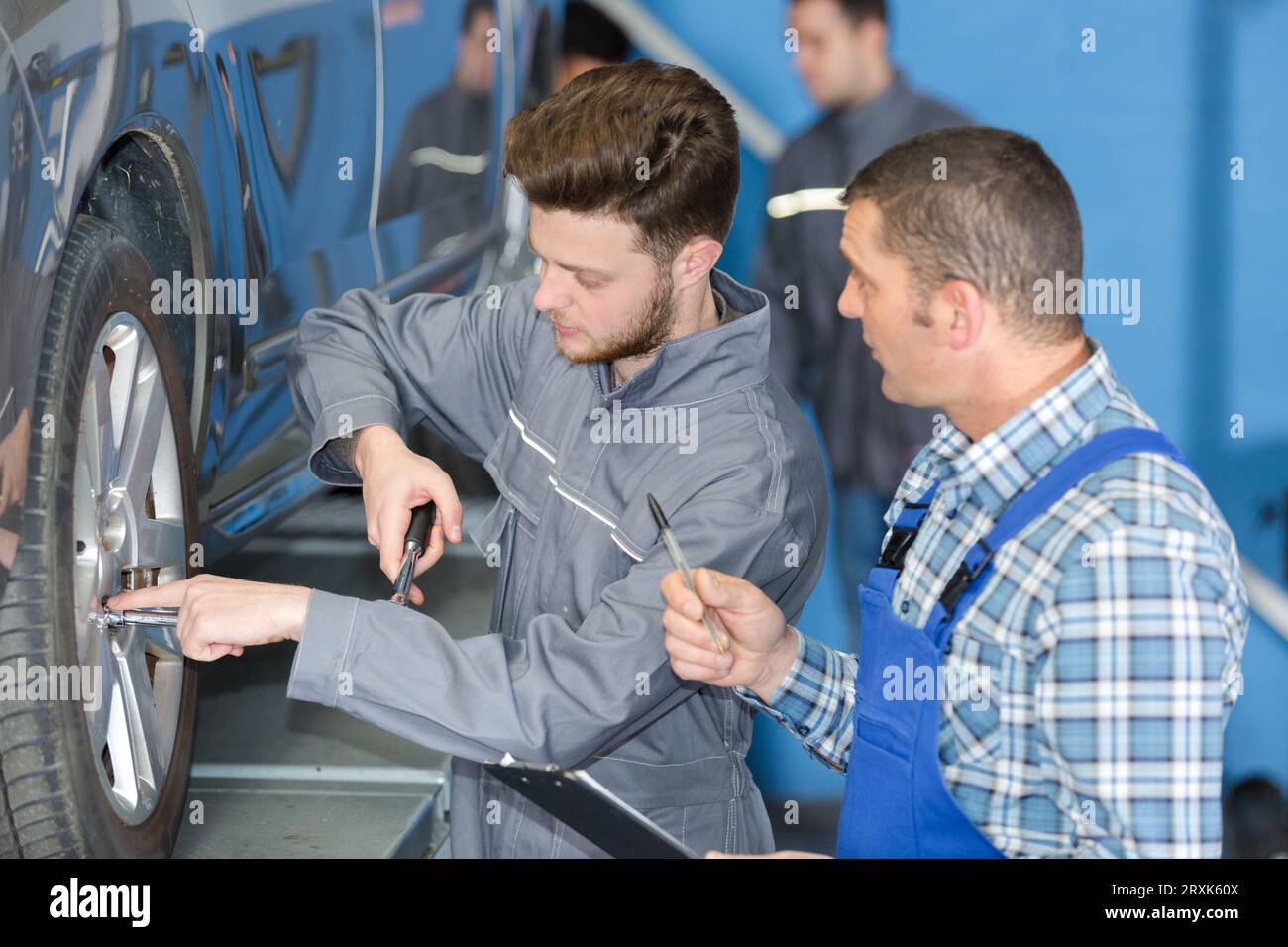 professional car mechanic apprentice changing car wheel with a wrench ...