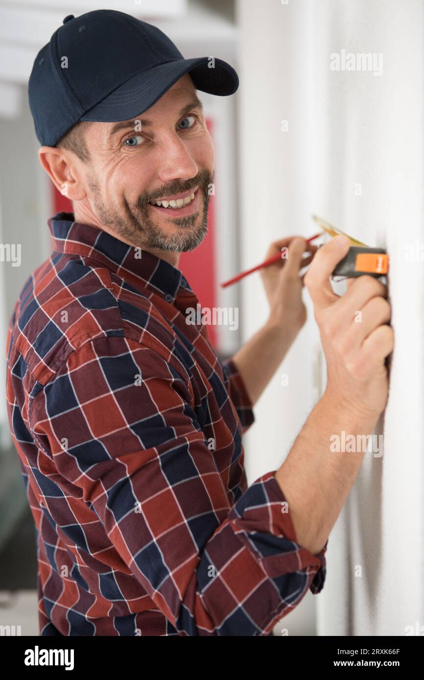 happy man measuring the wall with a measuring tape Stock Photo - Alamy