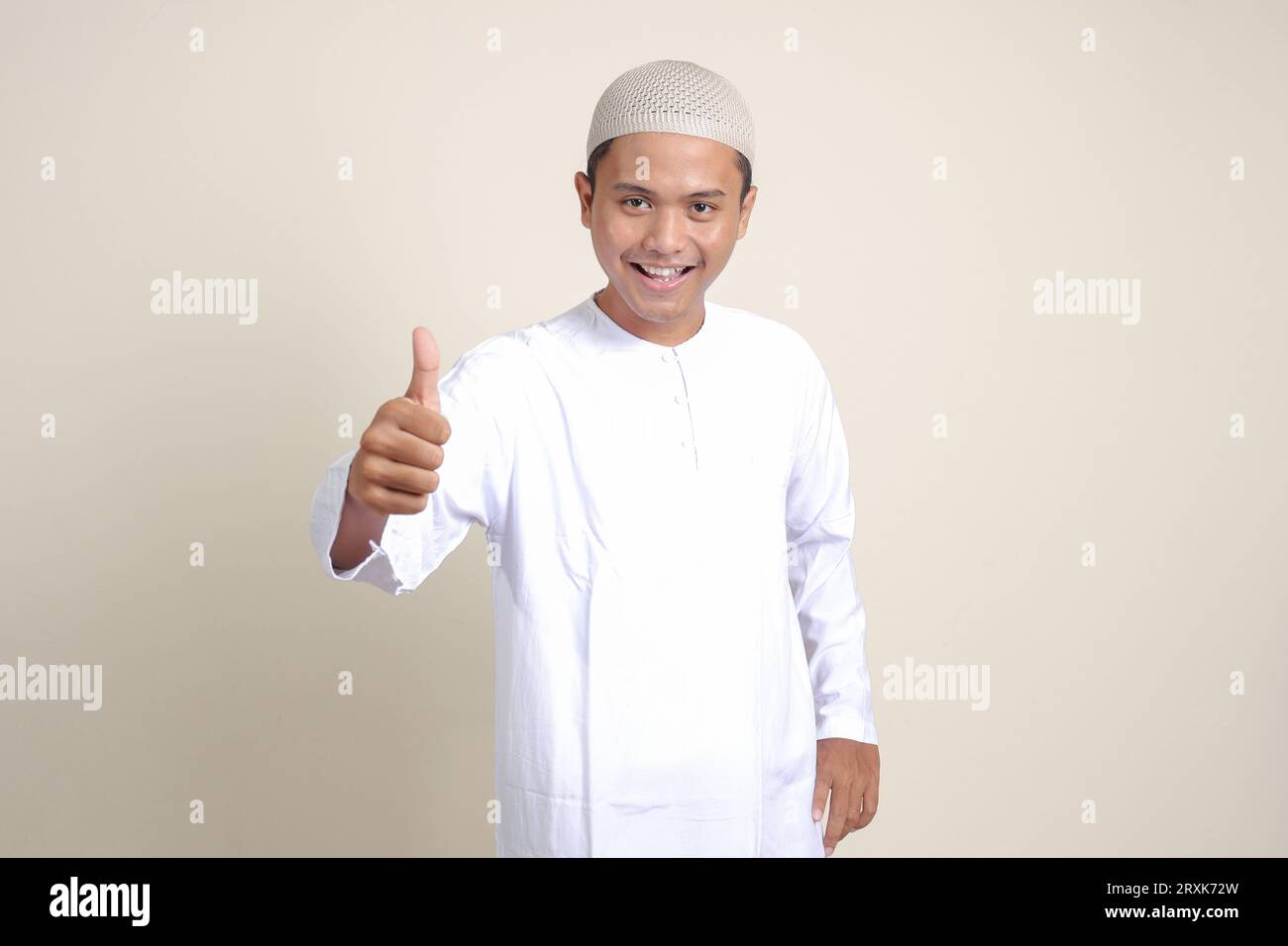 Portrait of attractive Asian muslim man in white shirt showing thumb up ...