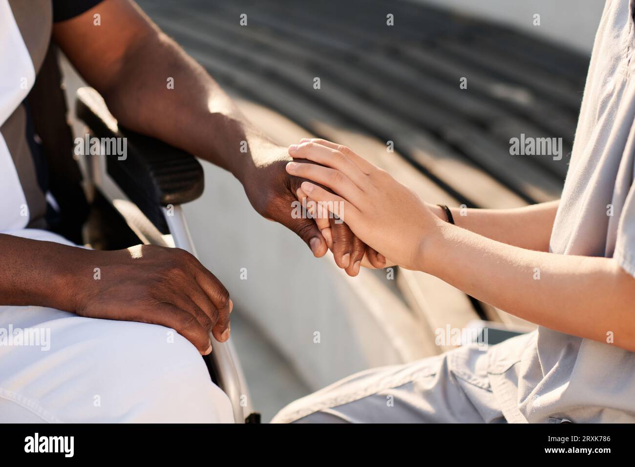Close-up of caregiver holding hands with man with disability and ...
