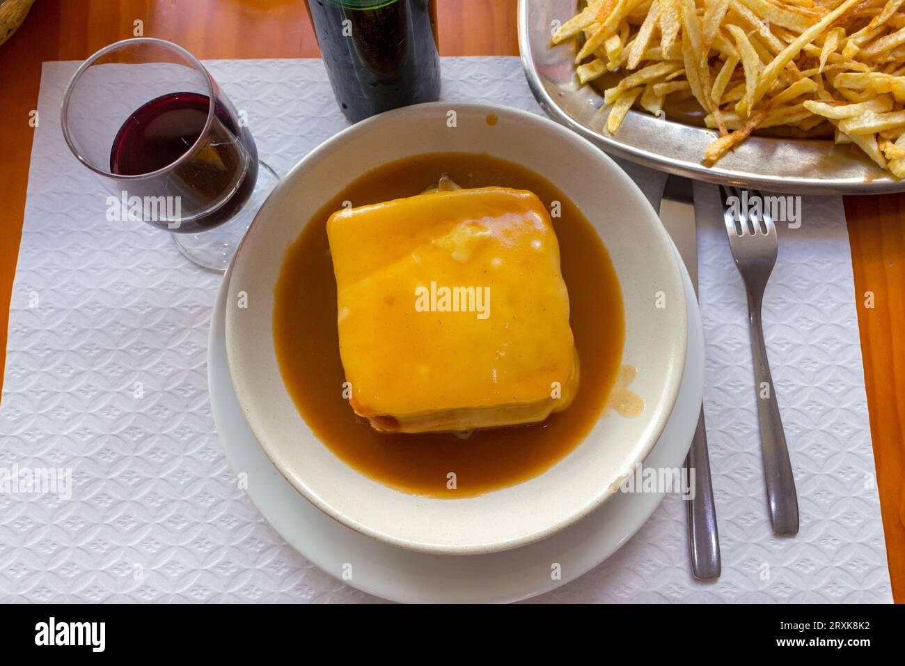 Traditional portuguese sandwich francesinha with glass of wine and ...