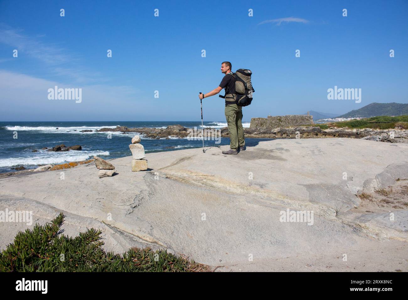 Tourist with big backpack and sticks on coast of Atlantic ocean ...