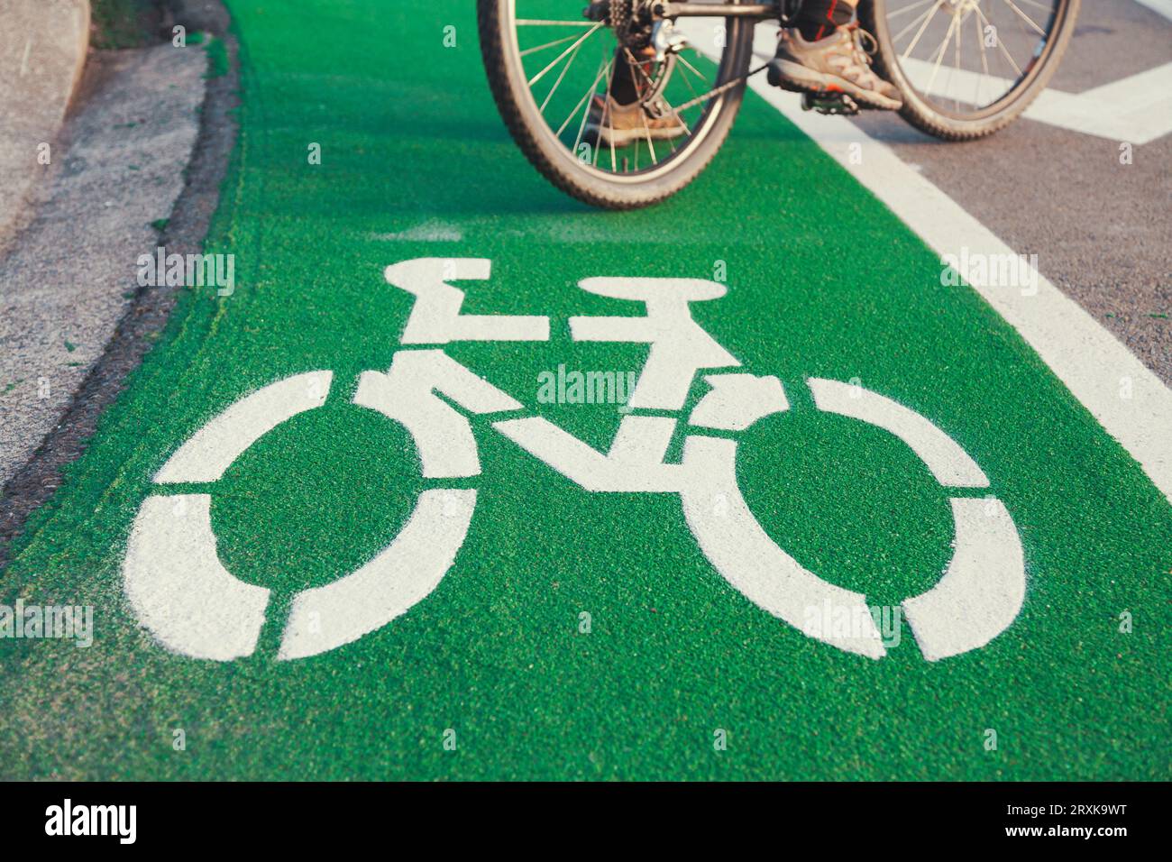 Green cycle path with painted bicycle lane sign and cyclist in ...