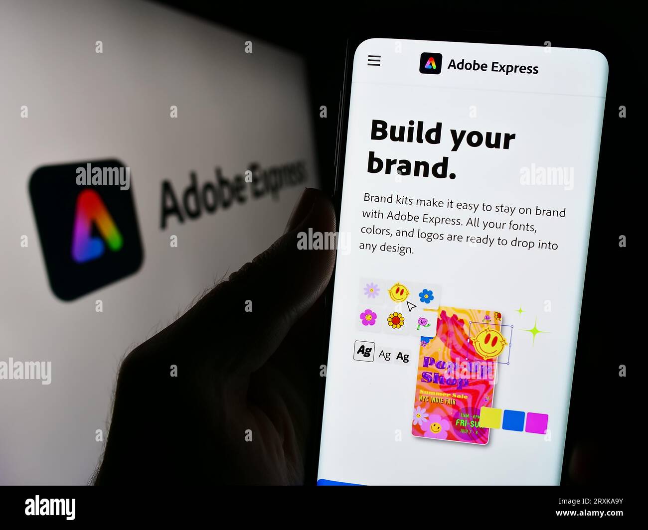 Person holding cellphone with webpage of graphics design software Adobe ...