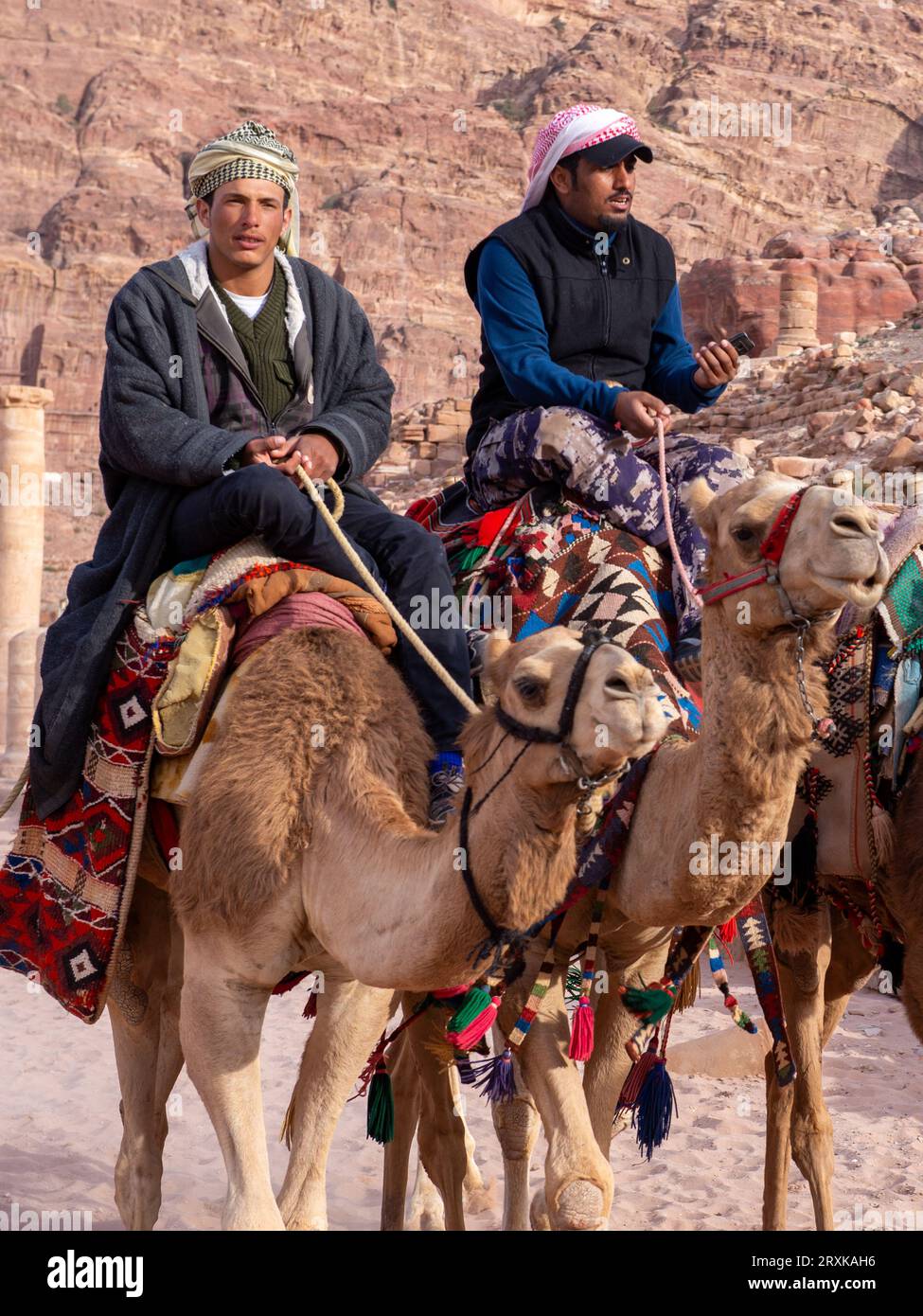 Locals wearing Keffiyeh riding camels in Petra, Jordan Stock Photo - Alamy