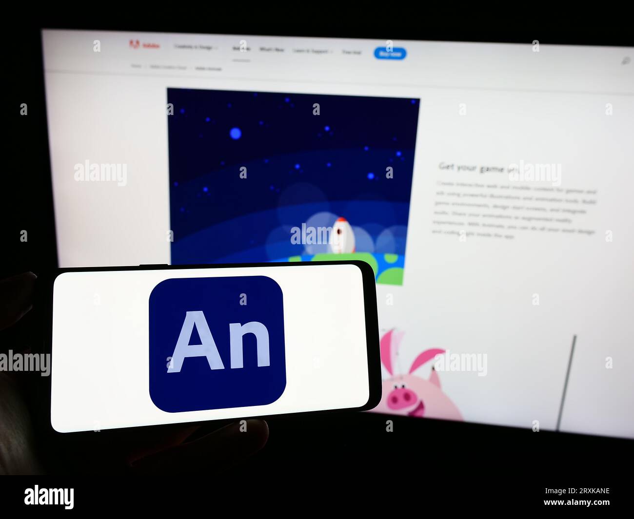 Person holding cellphone with logo of computer animation software Adobe ...