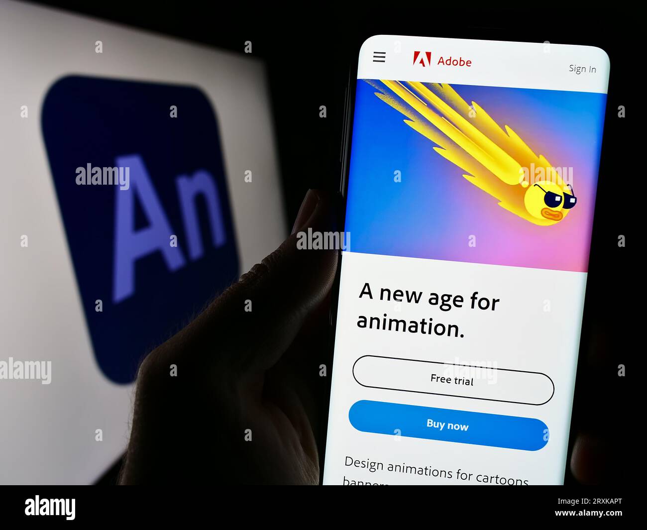 Person Holding Cellphone With Website Of Computer Animation Software Adobe Animate On Screen In